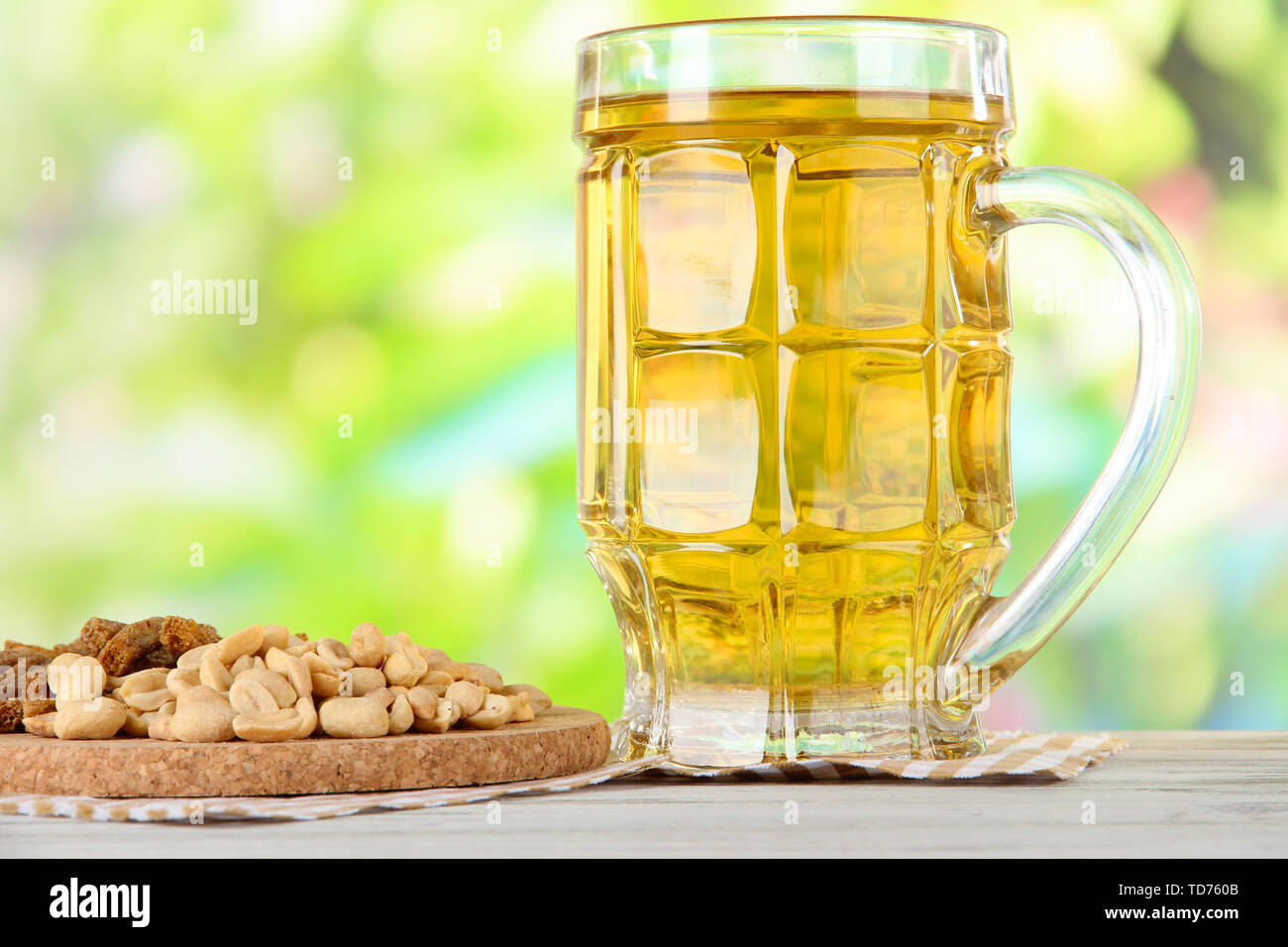 Beer in glass crunches, and nuts on napkin on table on nature ...