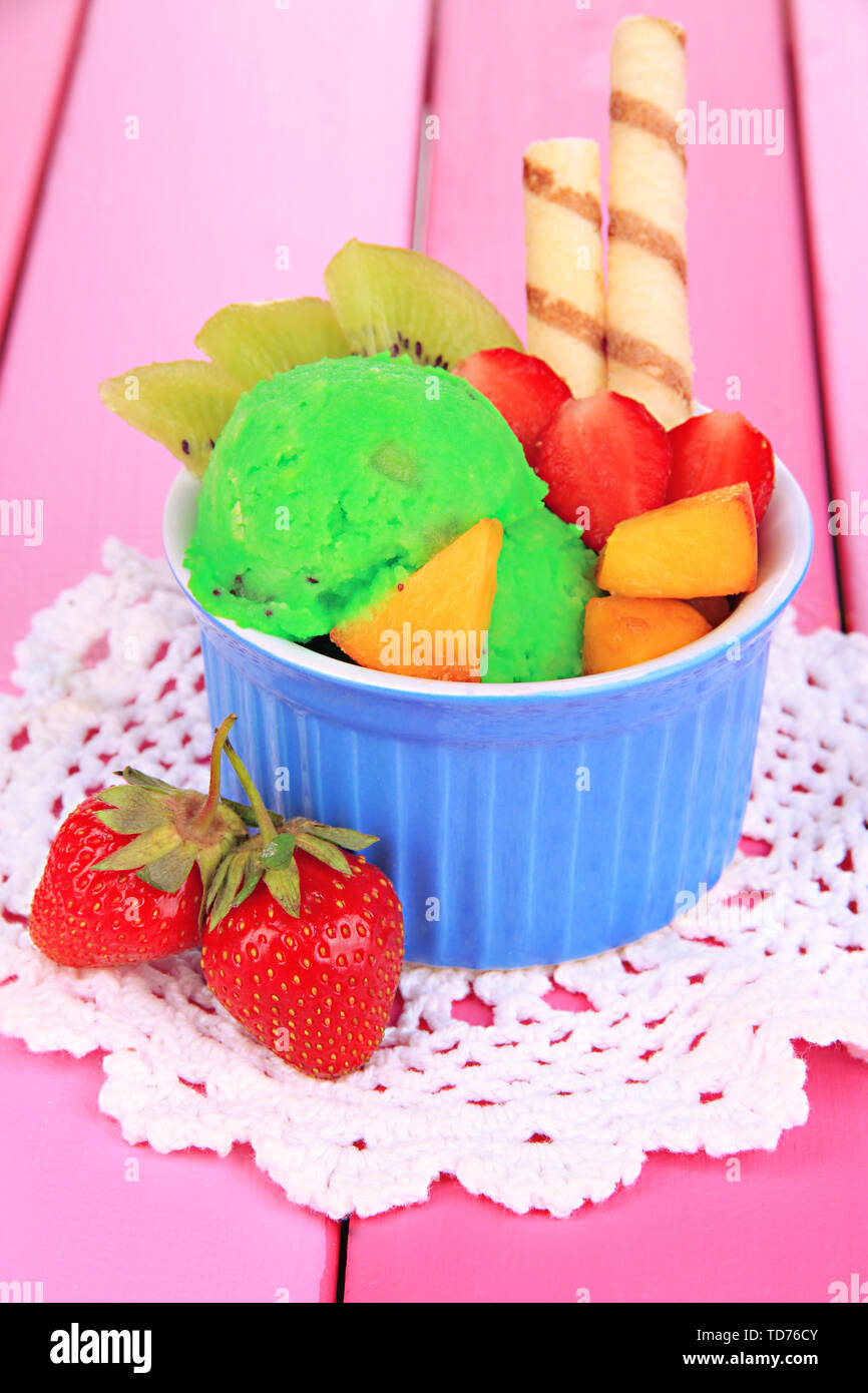 Delicious ice cream with fruits and berries in bowl on wooden table ...