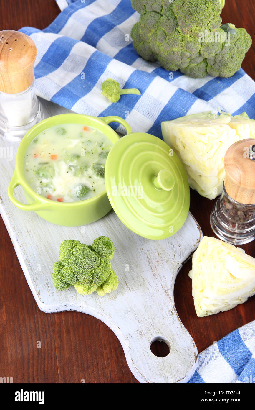 Cabbage soup in plate on board for cutting near napkin on wooden table ...