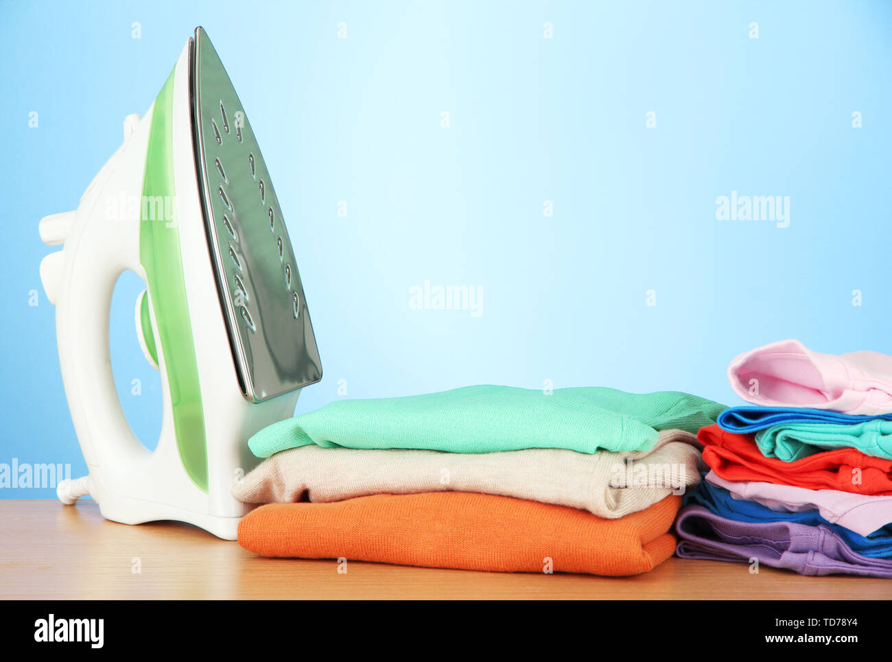 Steam iron with clothes, on color background Stock Photo - Alamy