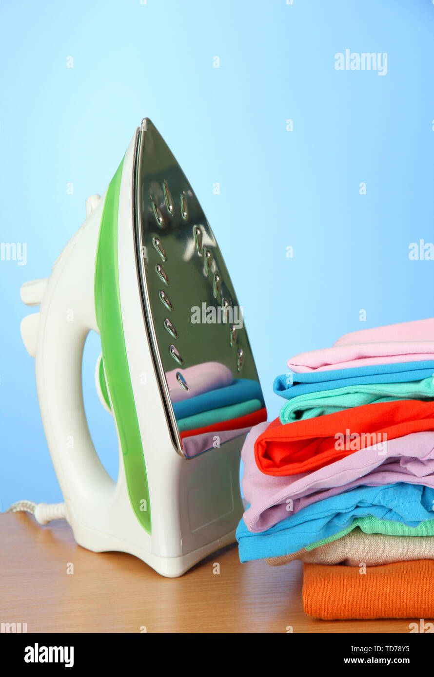 Steam iron with clothes, on color background Stock Photo - Alamy
