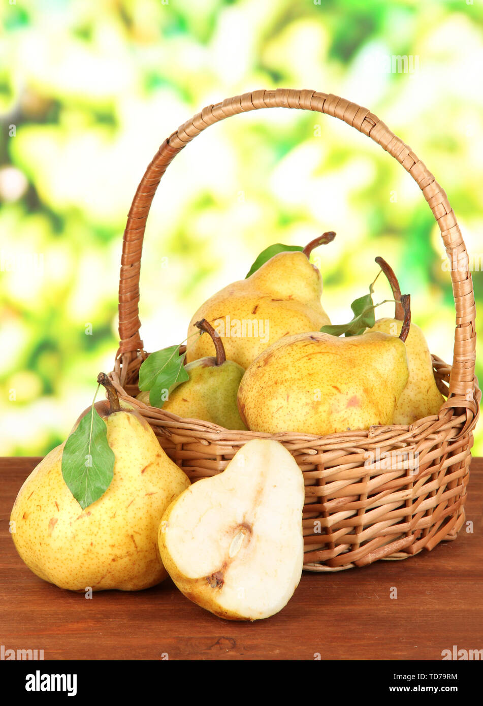 Juicy pears in wicker basket on table on bright background Stock Photo ...