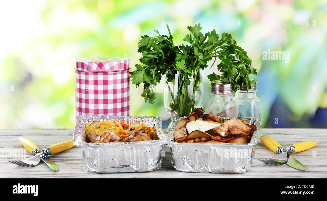 Food in boxes of foil on wooden table on nature background Stock Photo ...