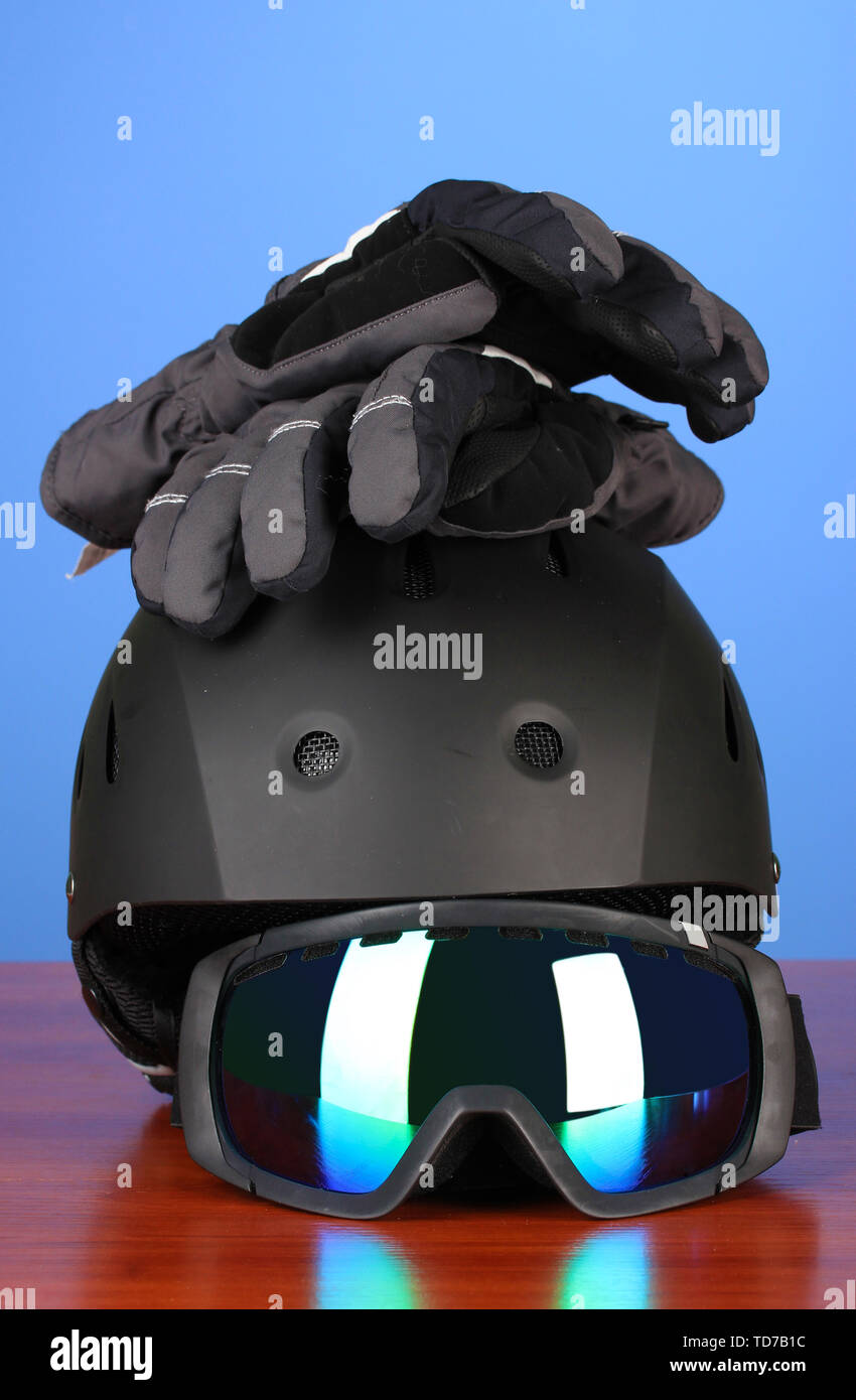 Winter sport glasses, helmet and gloves, on blue background Stock Photo ...
