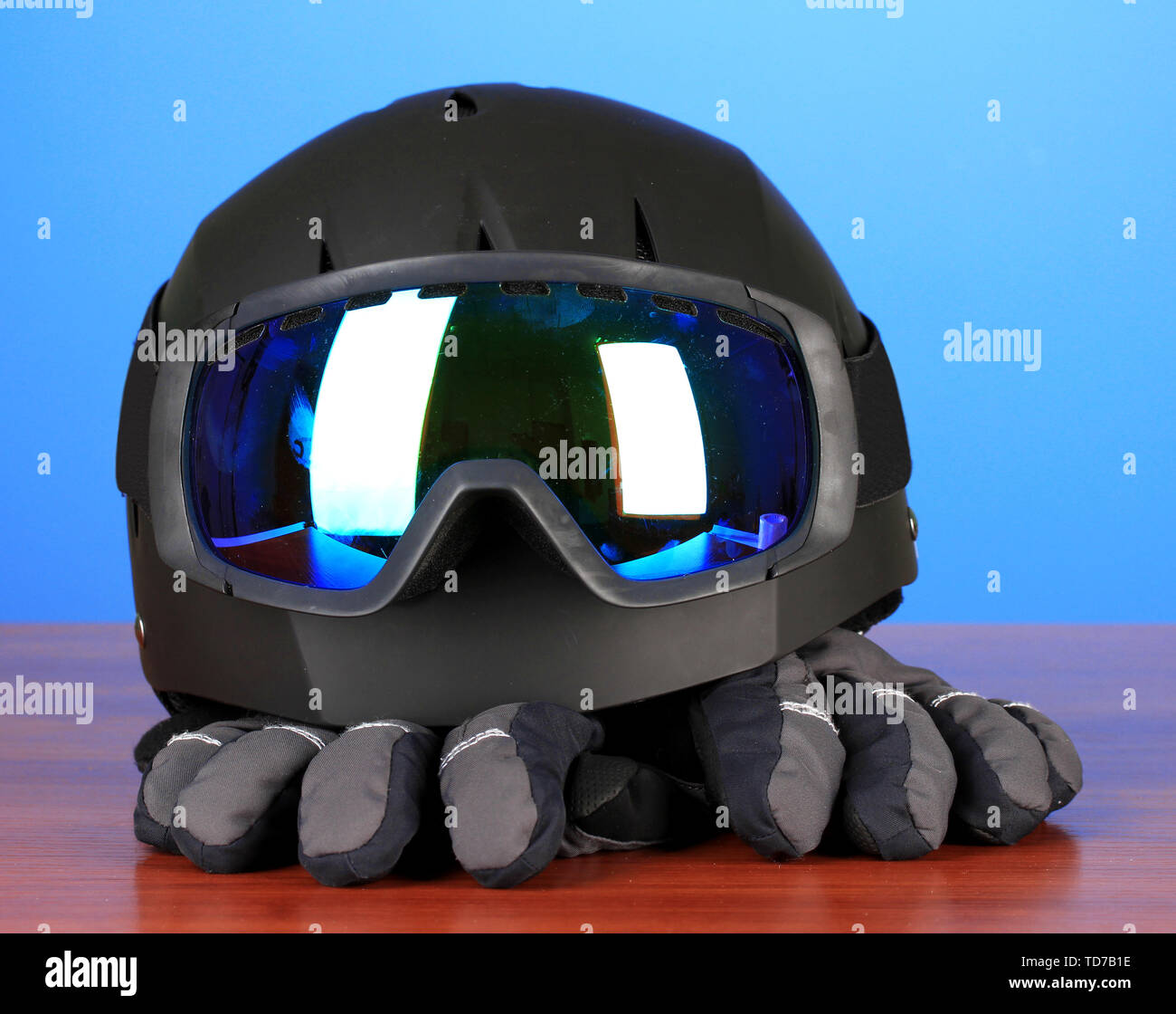 Winter sport glasses, helmet and gloves, on blue background Stock Photo ...