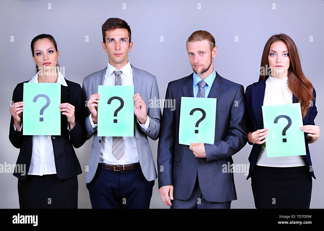 Business team standing in row with question mark on grey background ...