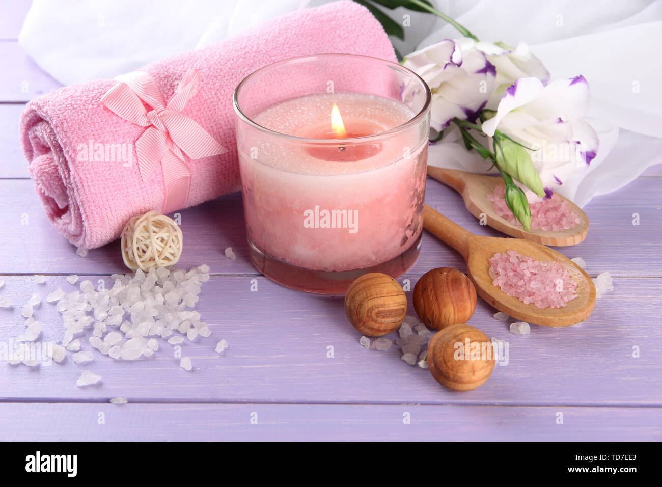 Beautiful spa setting with pink candle and flowers on purple wooden ...