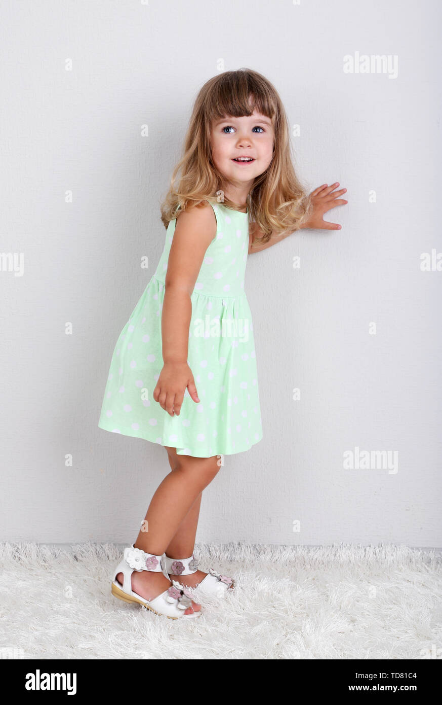 Little cute girl on carpet, on gray background Stock Photo - Alamy