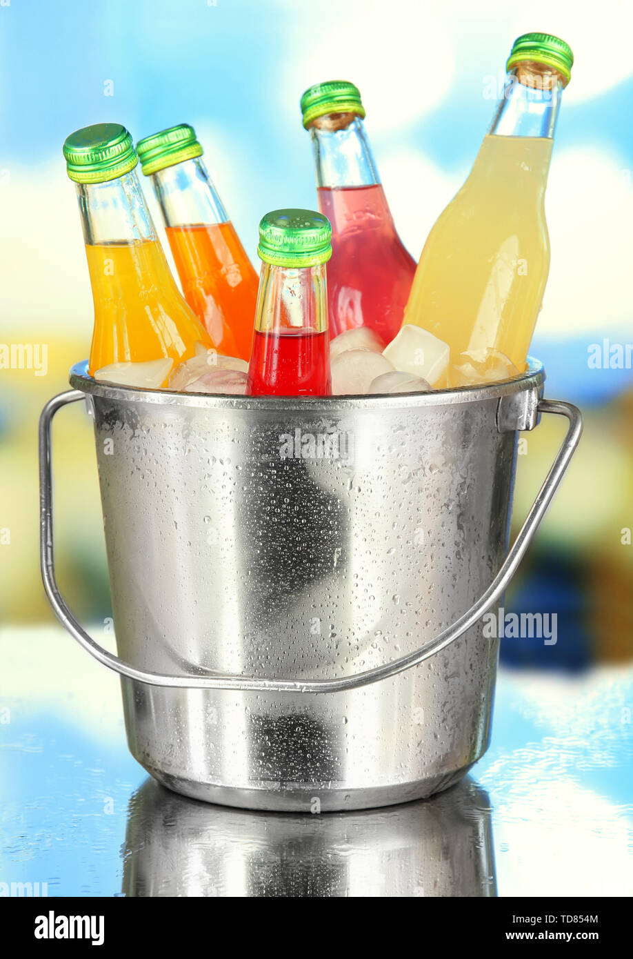 Bottles with tasty drinks in bucket with ice cubes, in bright ...