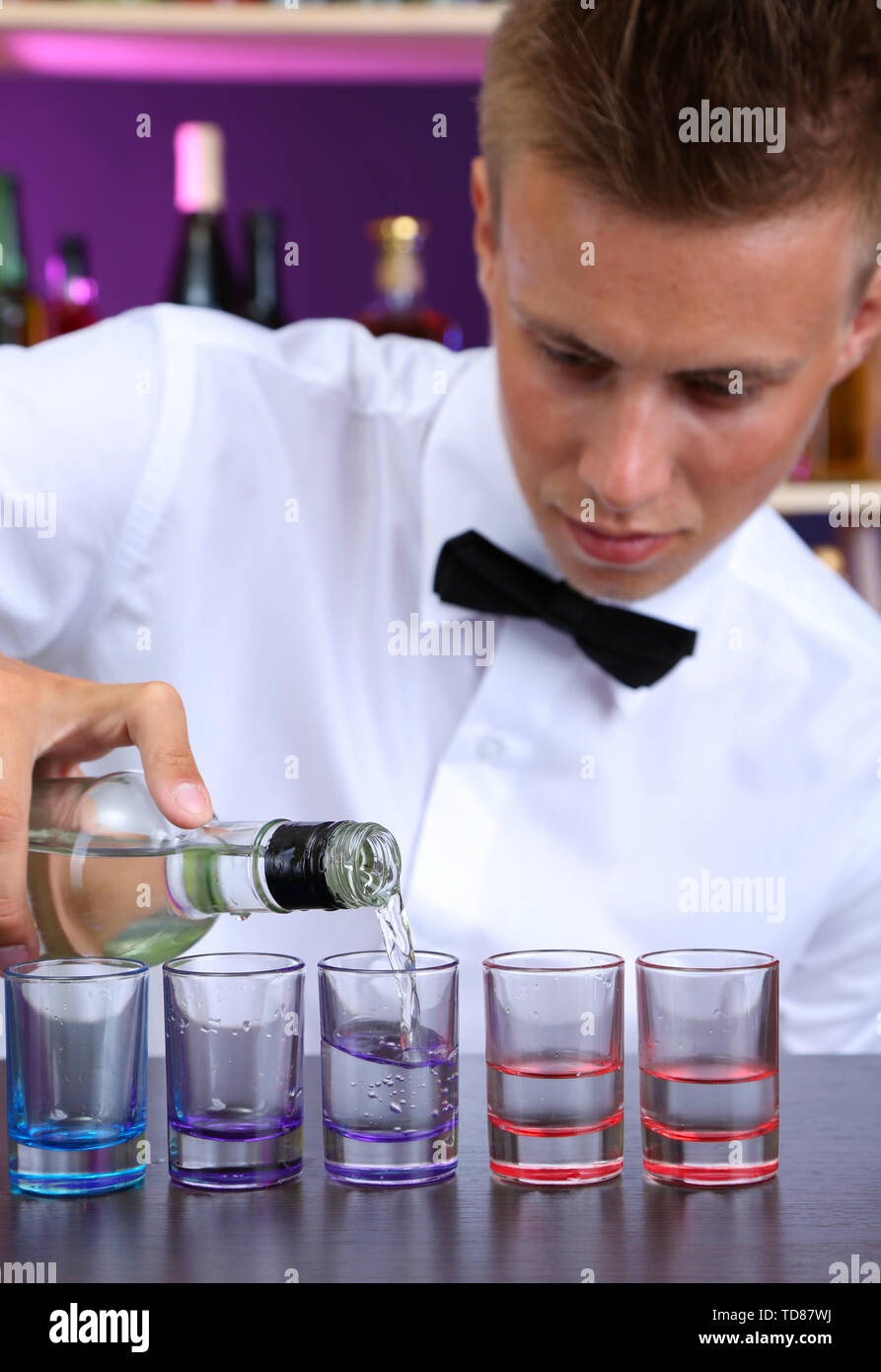 Bartender is pouring vodka into glasses Stock Photo - Alamy