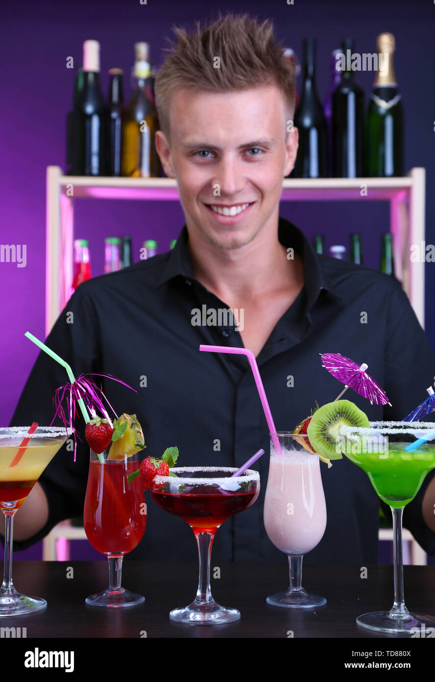 Portrait of handsome barman with different cocktails cocktail, at bar ...