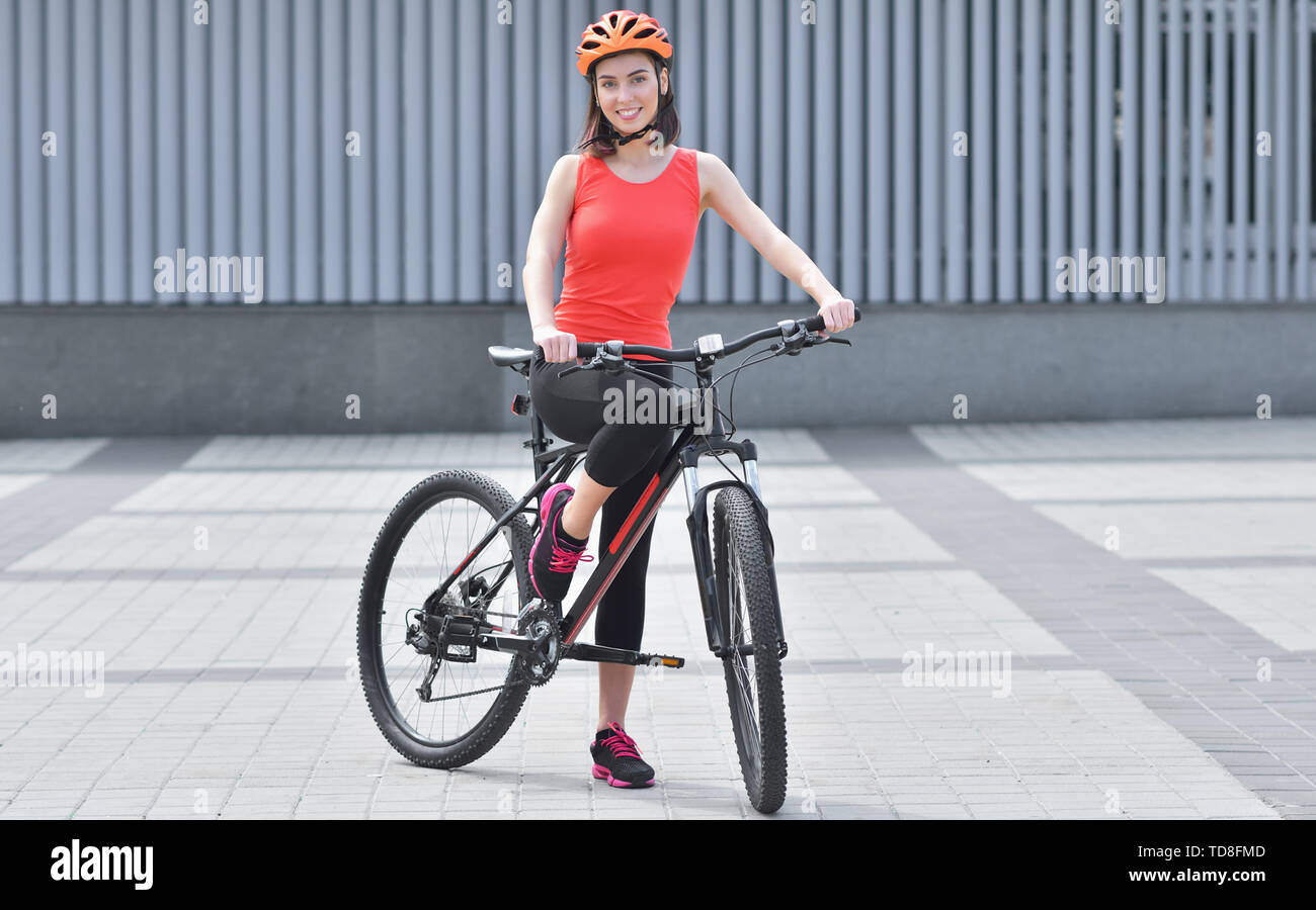 Fit girl wearing a tracksuit with helmet rides a bicycle through the ...