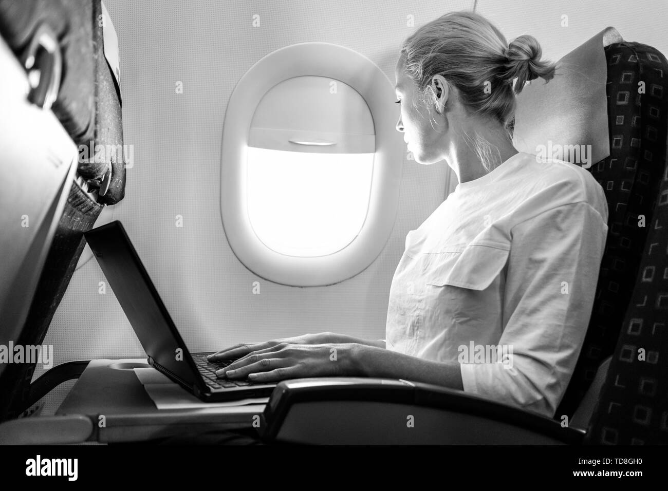 Attractive caucasian female passenger looking through the plain window ...