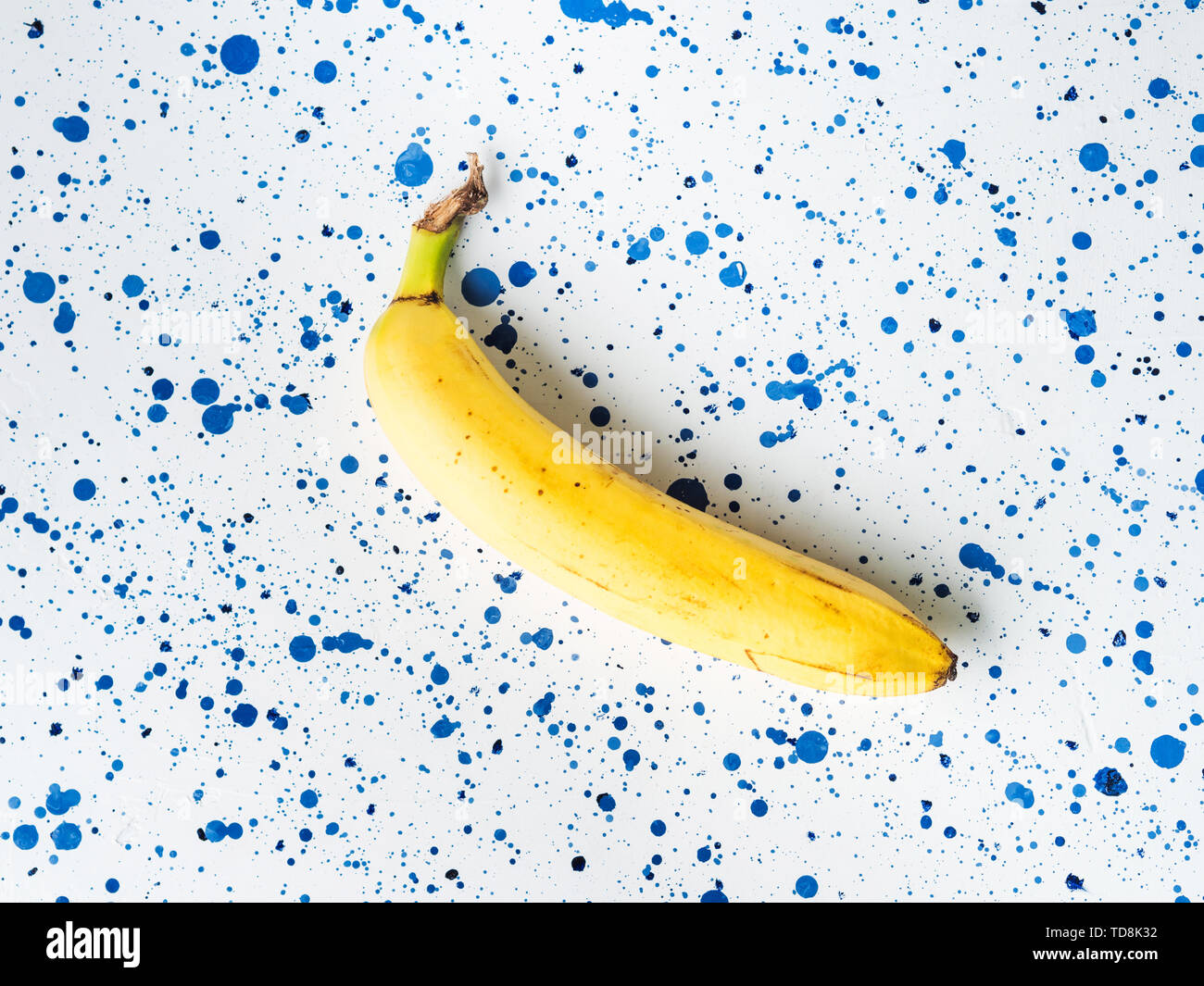 One banana laying on white and blue abstract backdrop Stock Photo - Alamy