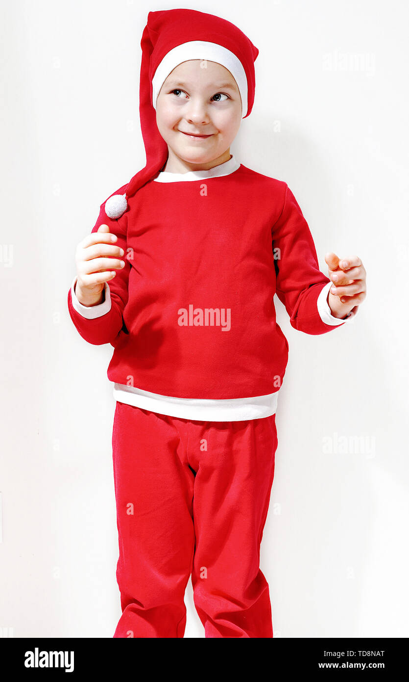 Little boy in the form of a Santa Claus smiling, standing on a white ...