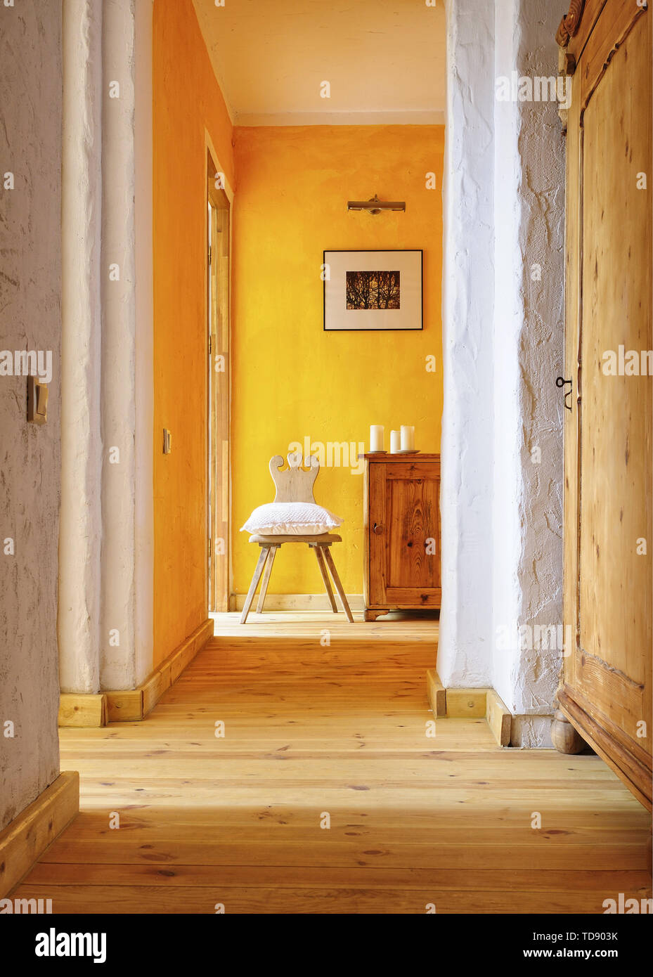 Chair placed at end of yellow country style hallway with wooden ...
