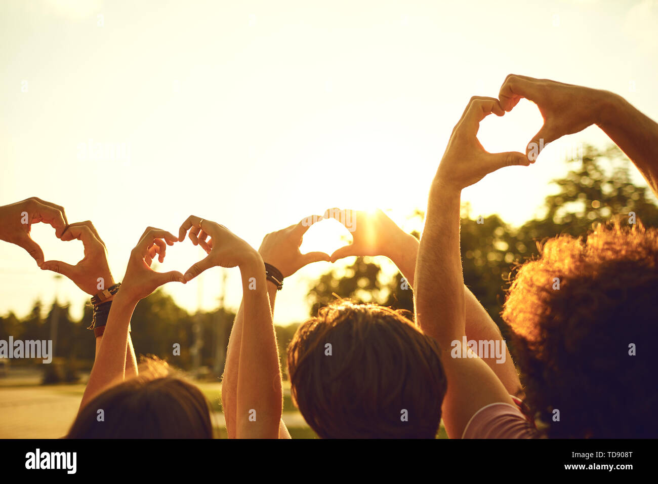Hands of group friends in the shape of a heart against the sunset. Love ...