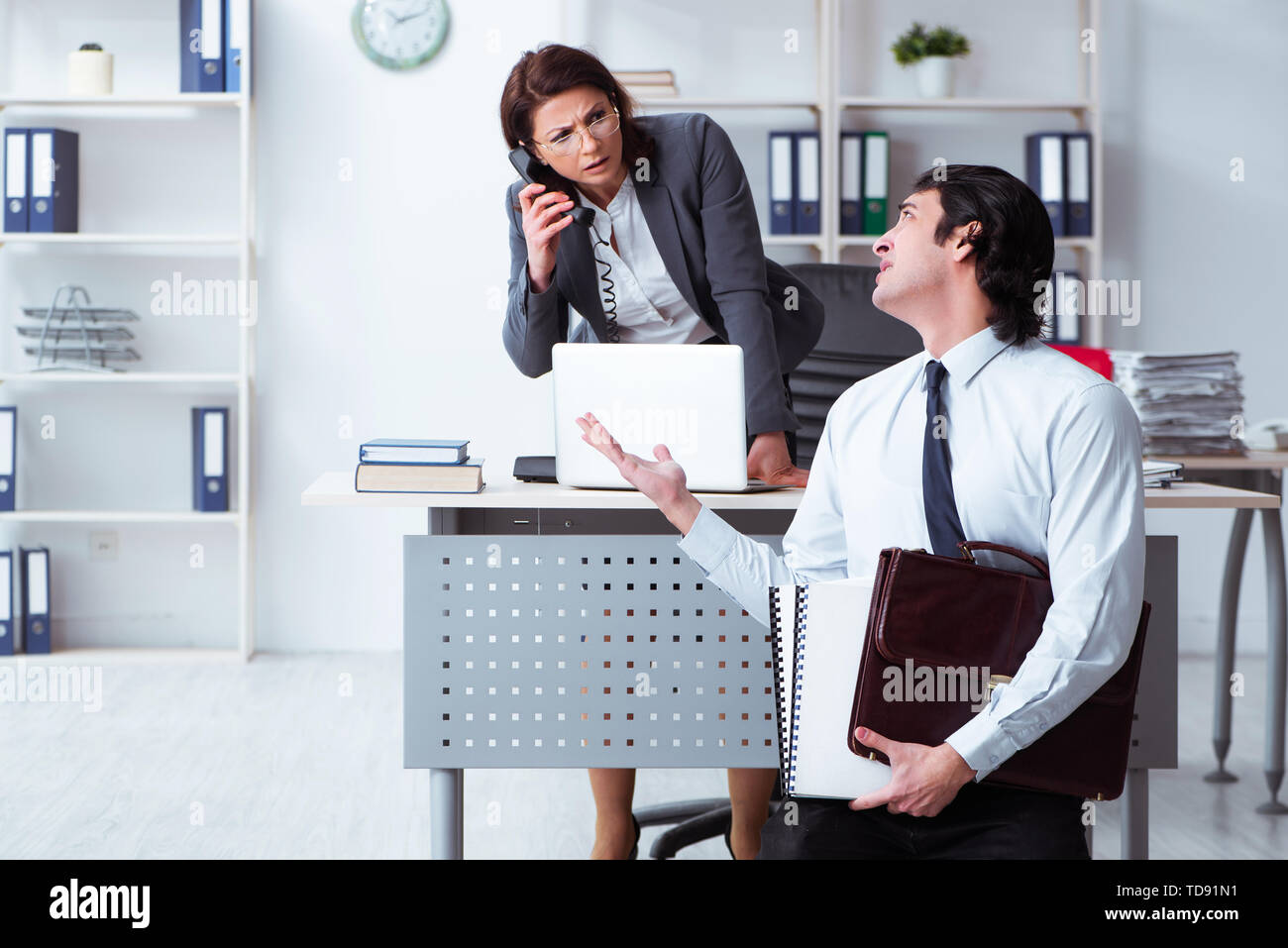 Old female boss and young male employee in the office Stock Photo - Alamy
