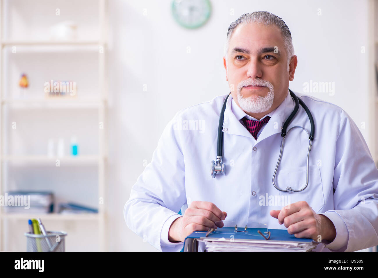 The old male doctor working in the clinic Stock Photo - Alamy