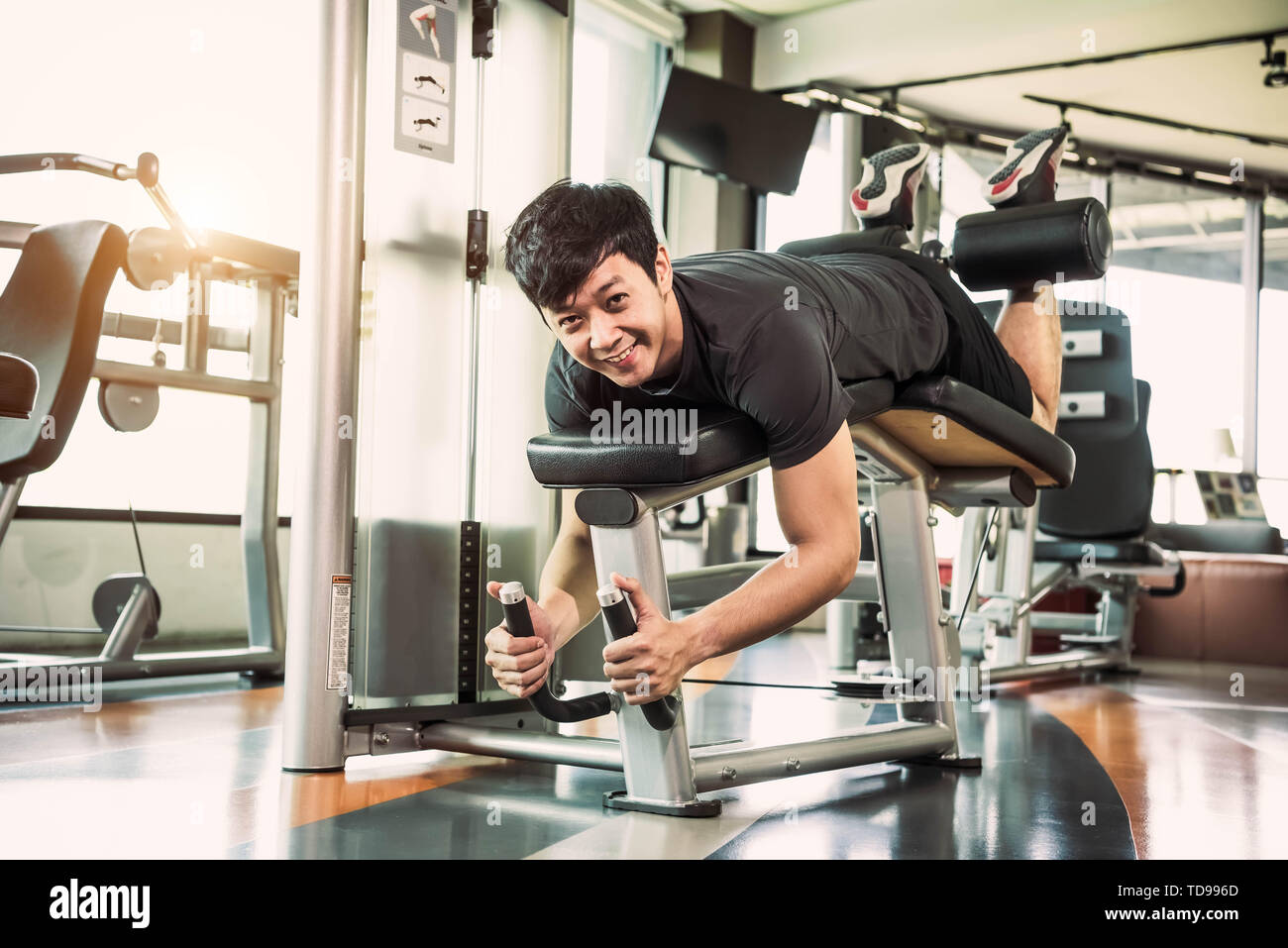 Asian sport man stretching and lifting weight by two legs when facing ...
