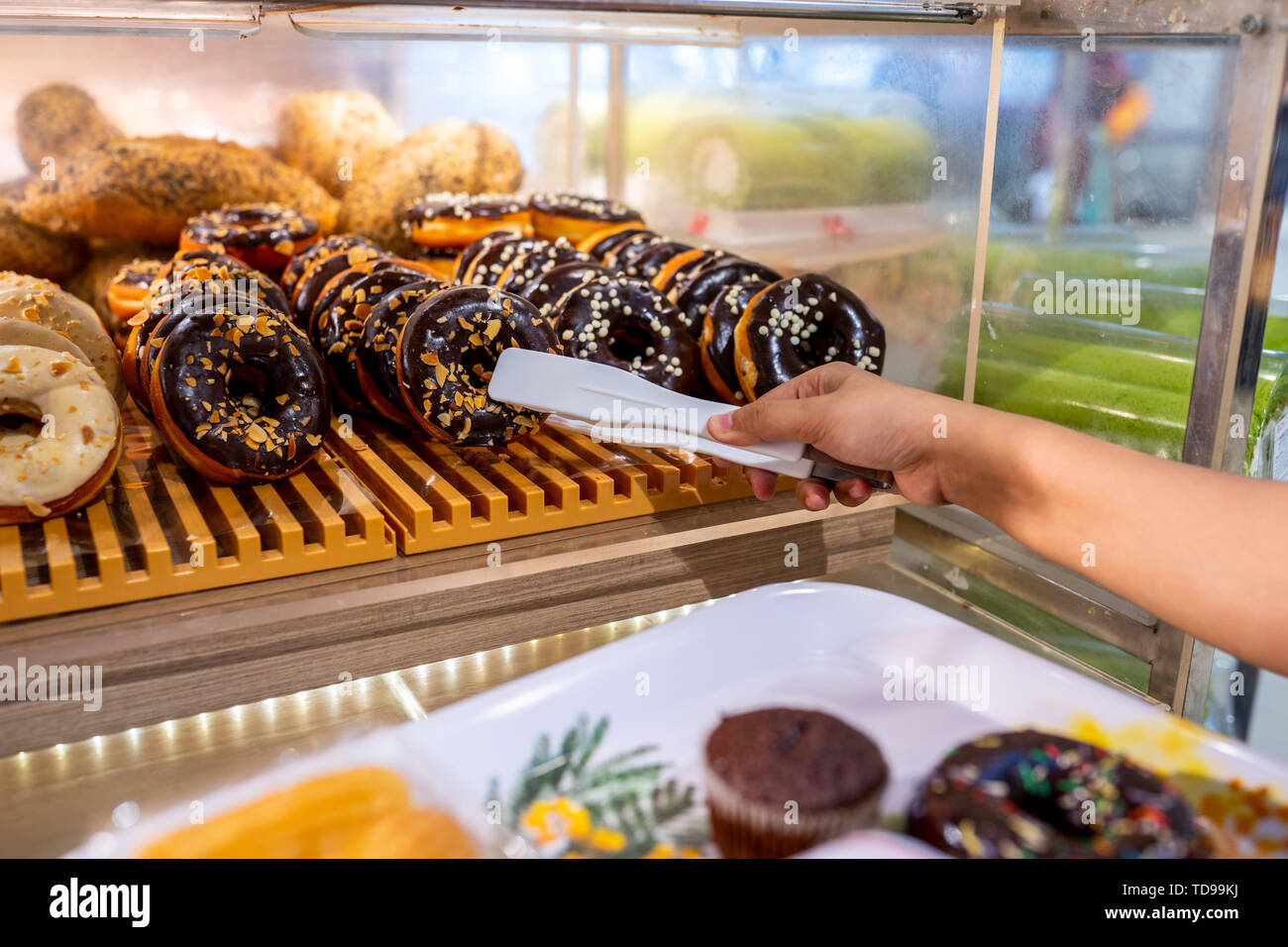 Human hand picking a delicious chocolate donut by clamp Stock Photo - Alamy