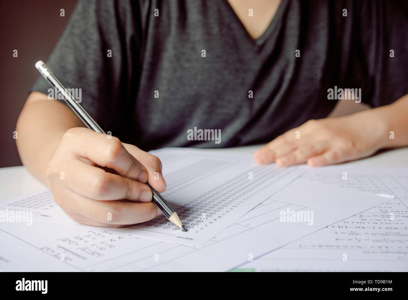 Students hand holding pencil writing selected choice on answer sheets ...