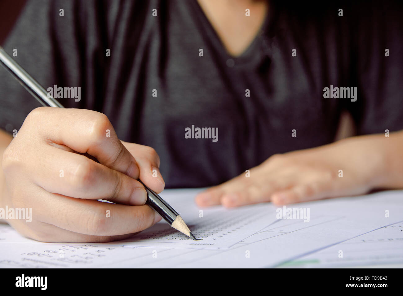 Students hand holding pencil writing selected choice on answer sheets ...