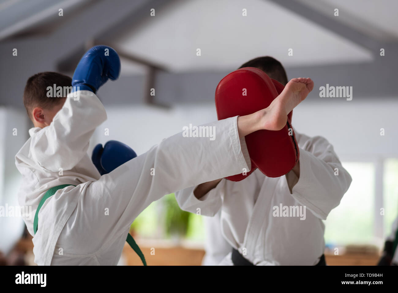 Fight with trainer. Boy wearing white kimono and blue protective gloves ...