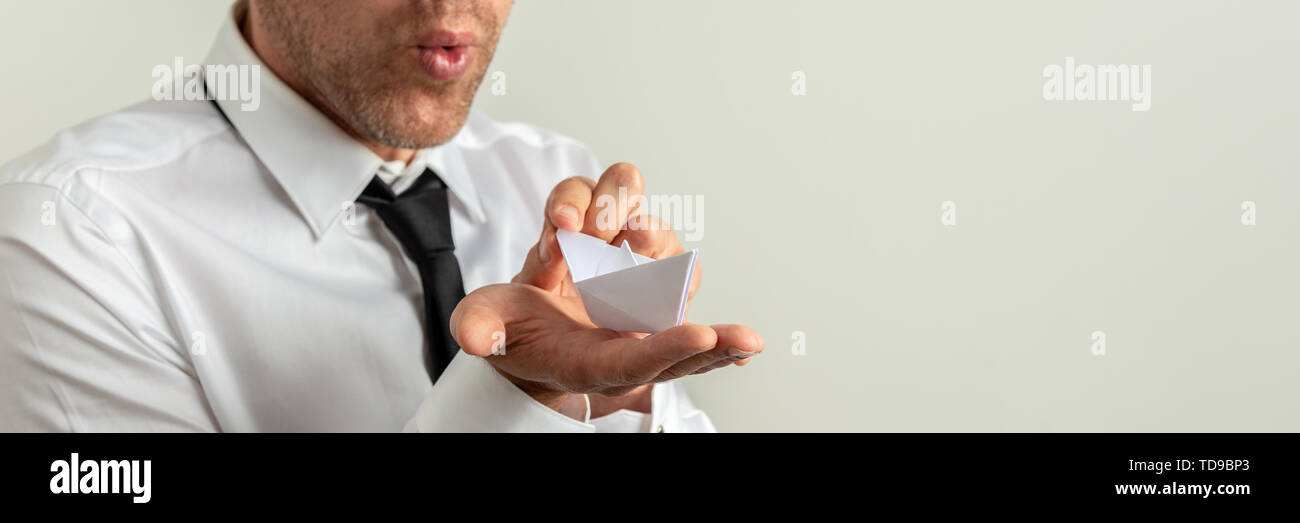 Wide view image of businessman holding an origami paper made boat in ...