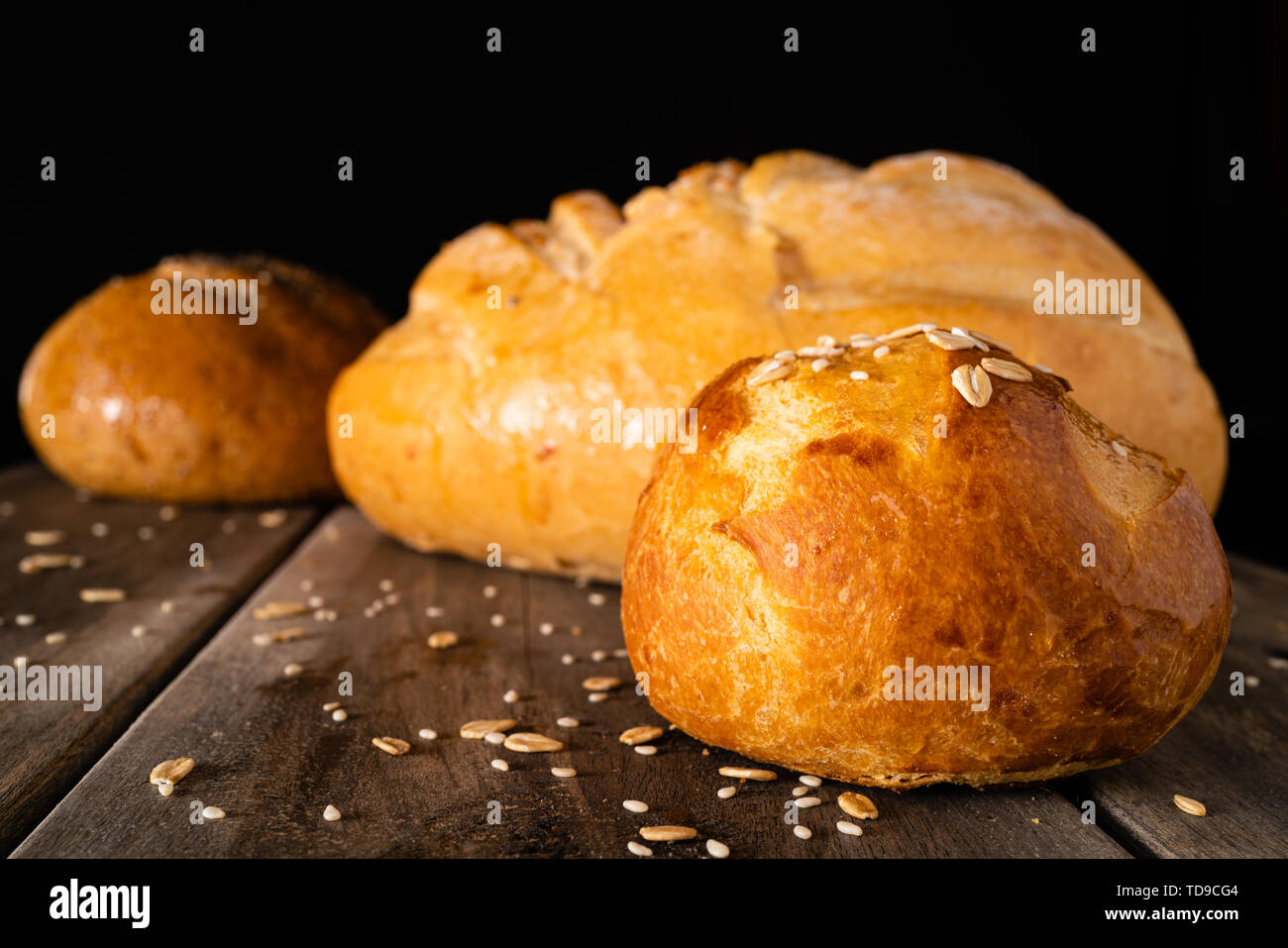 Three loaves of bread on an old wooden table with a dark background ...