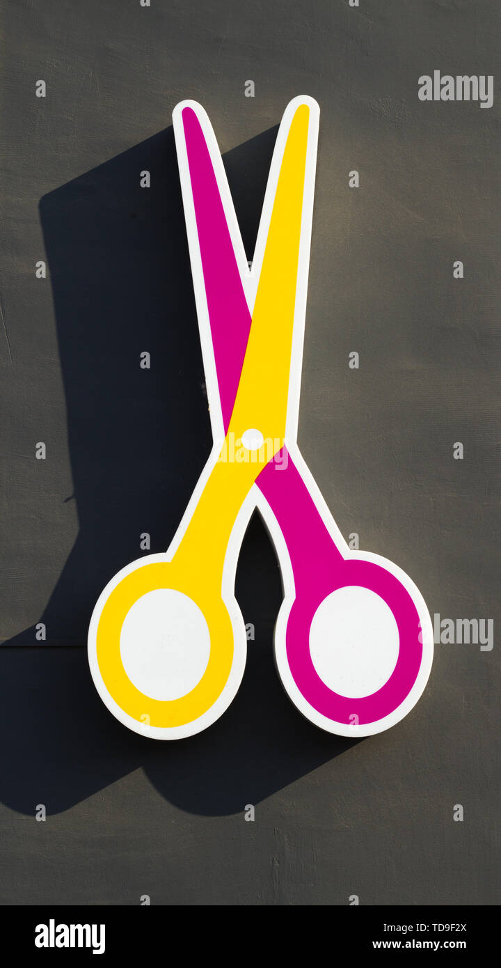 Isolated big colorful scissors sign hanging on the wall. Gdansk ...