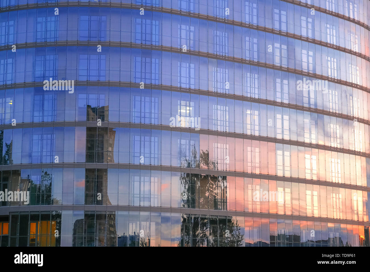 Modern multi-storey building with a glass facade. The evening sunset ...