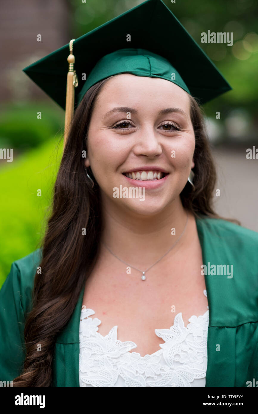 University graduate on her college campus in a cap and gown celebrating ...