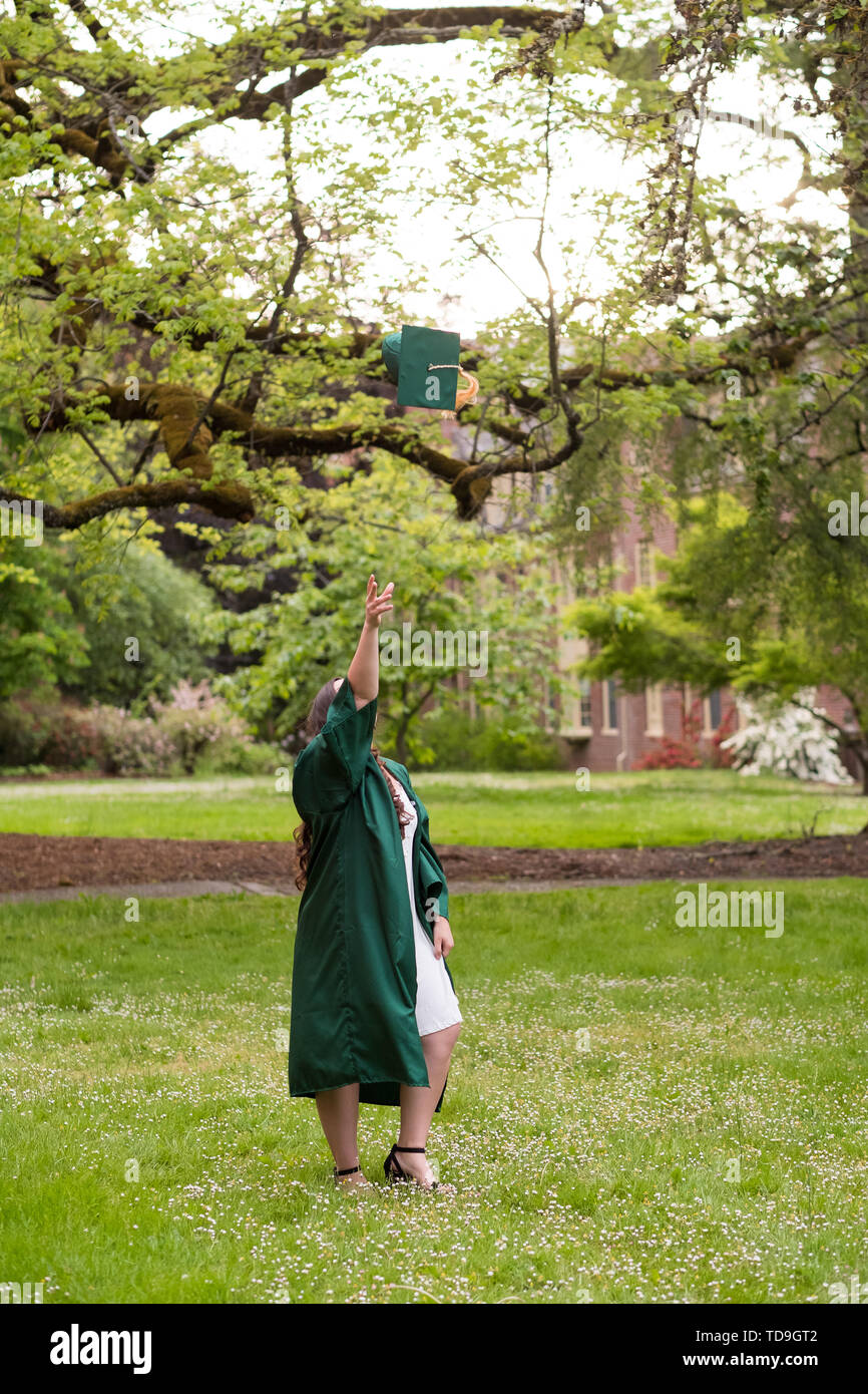 University graduate on her college campus in a cap and gown celebrating ...