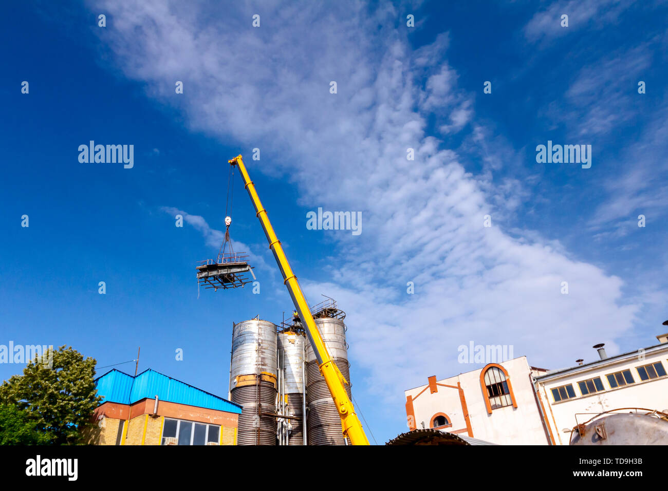 Crane is bringing down part of heavy metal construction in industrial ...