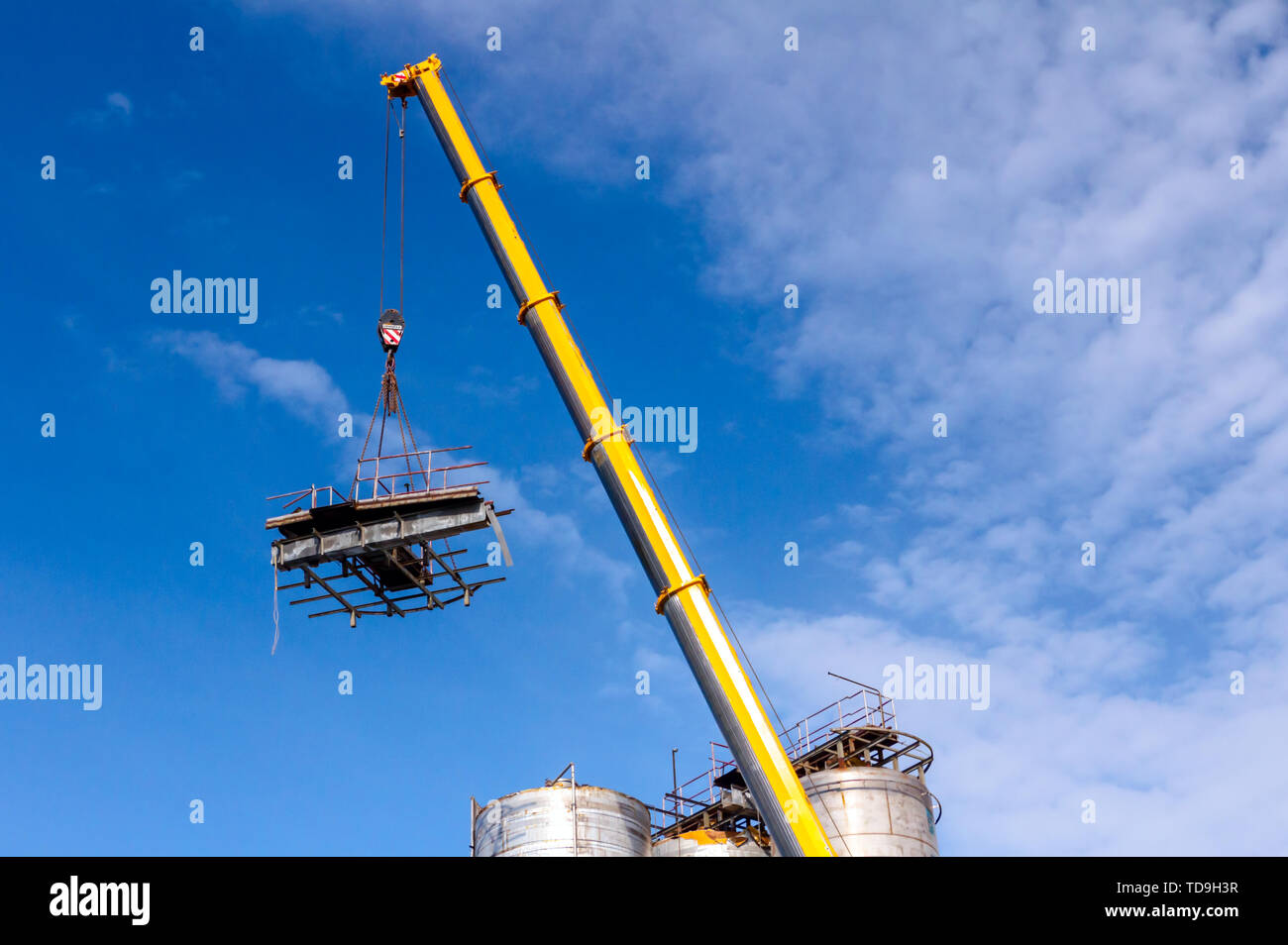 Crane is bringing down part of heavy metal construction in industrial ...