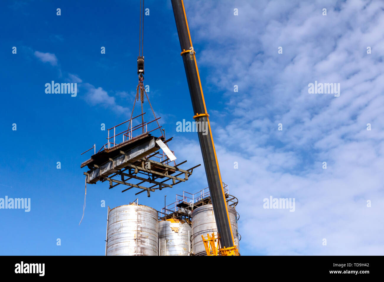 Crane is bringing down part of heavy metal construction in industrial ...
