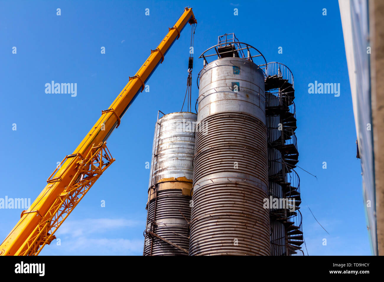 Crane is carry and keeps balance with heavy metal silo in industrial ...