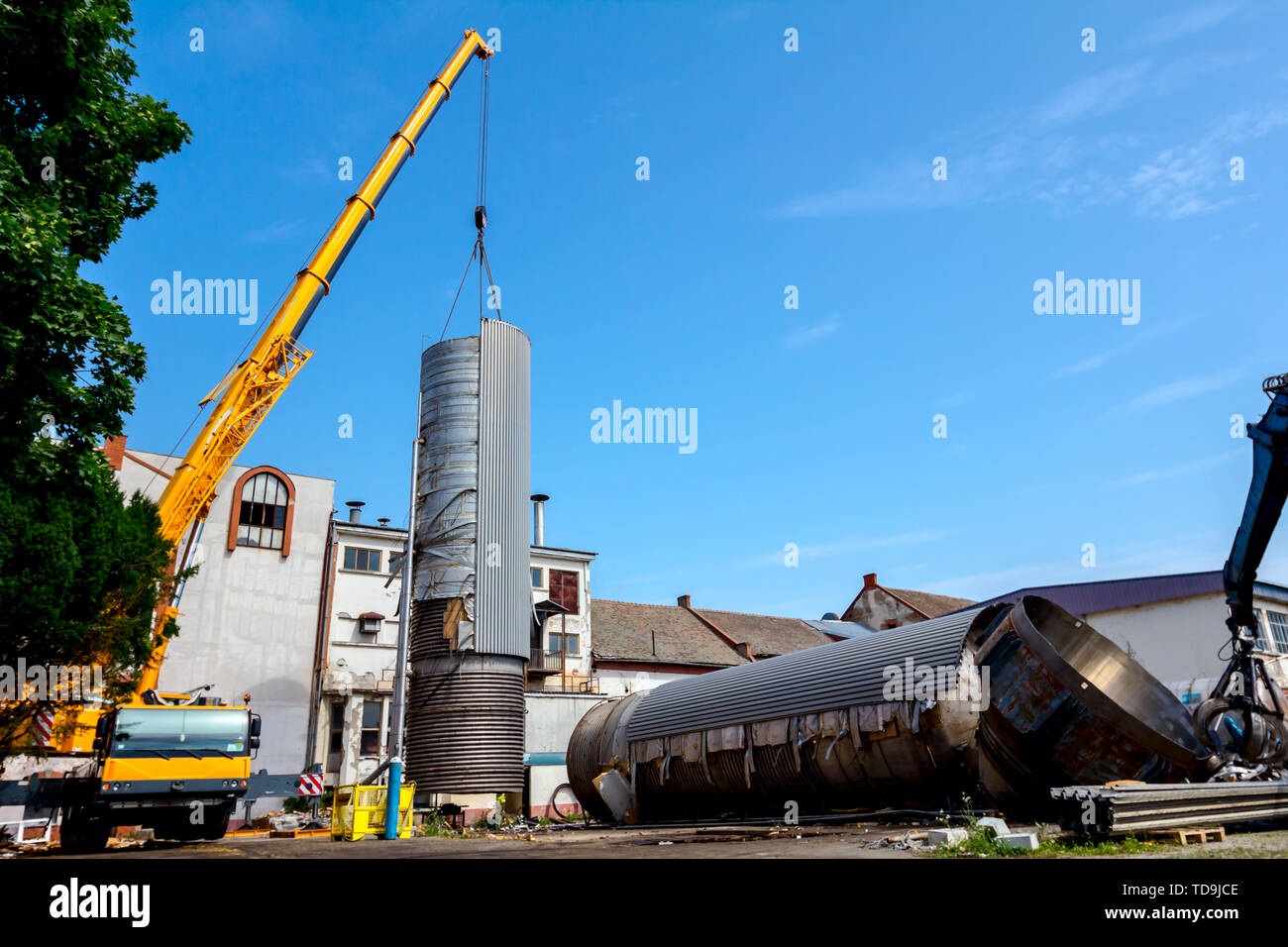 Crane is bringing down heavy metal silo in industrial complex Stock ...