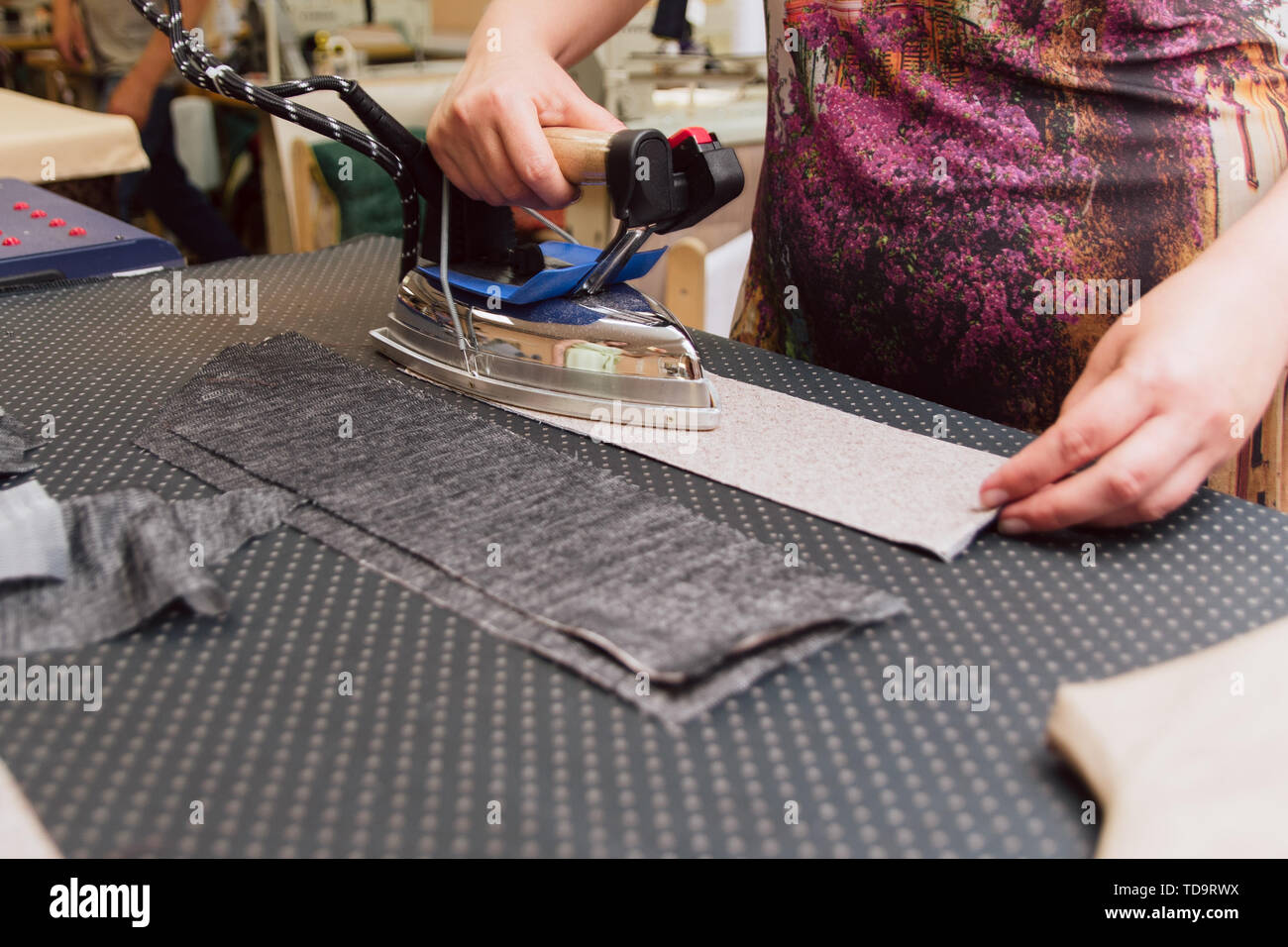 A woman strokes the fabric for further sewing. Tailor ironing clothes ...