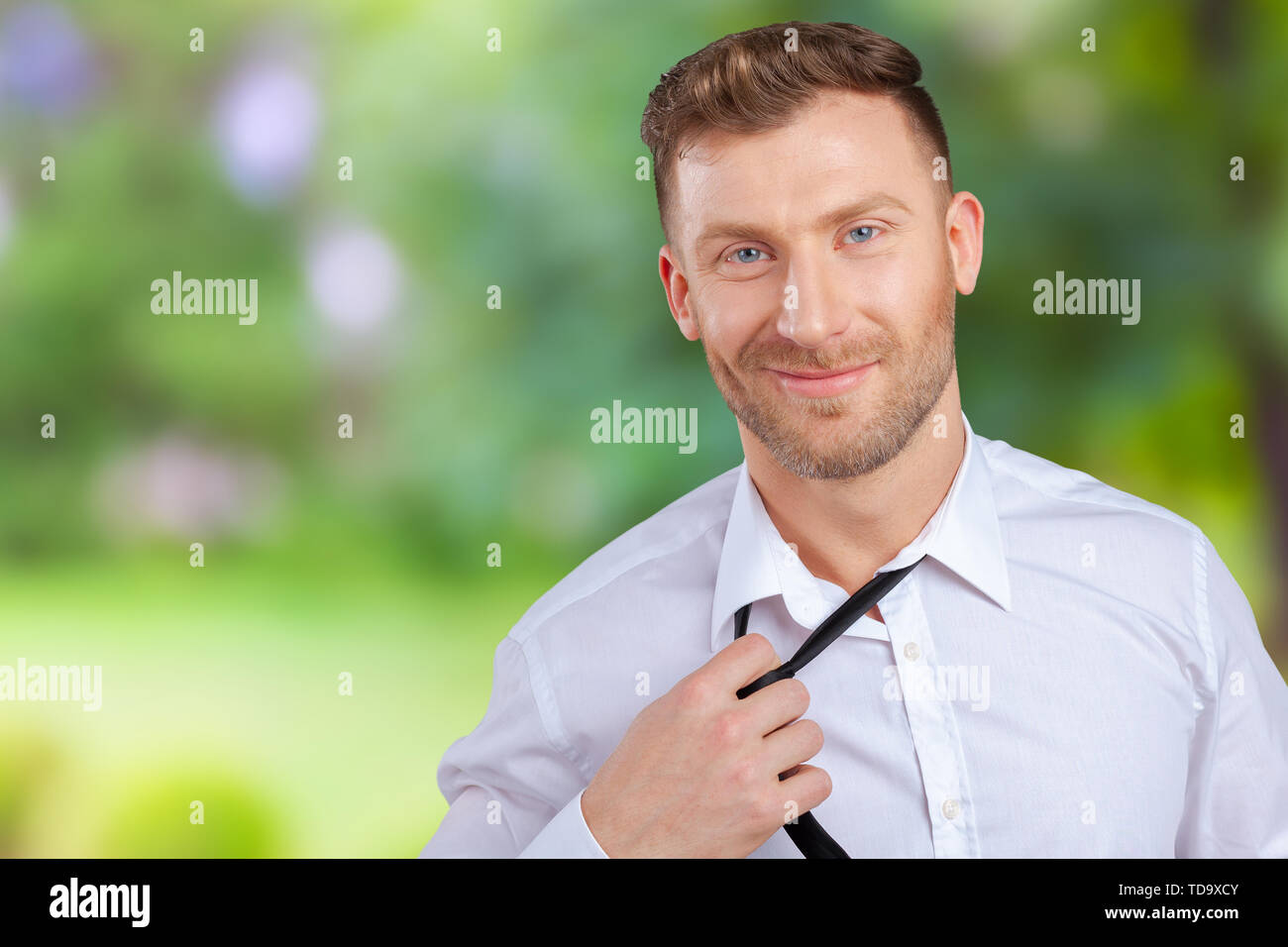 Confident young man in shirt and tie adjusting his necktie Stock Photo ...