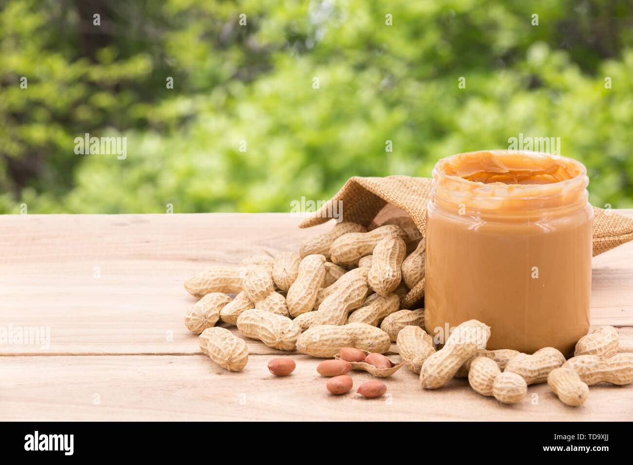 Peanut butter and peanuts on wooden table Stock Photo - Alamy