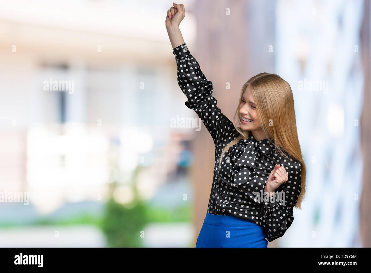 Pretty young blonde woman throwing her arms up into the air in ...