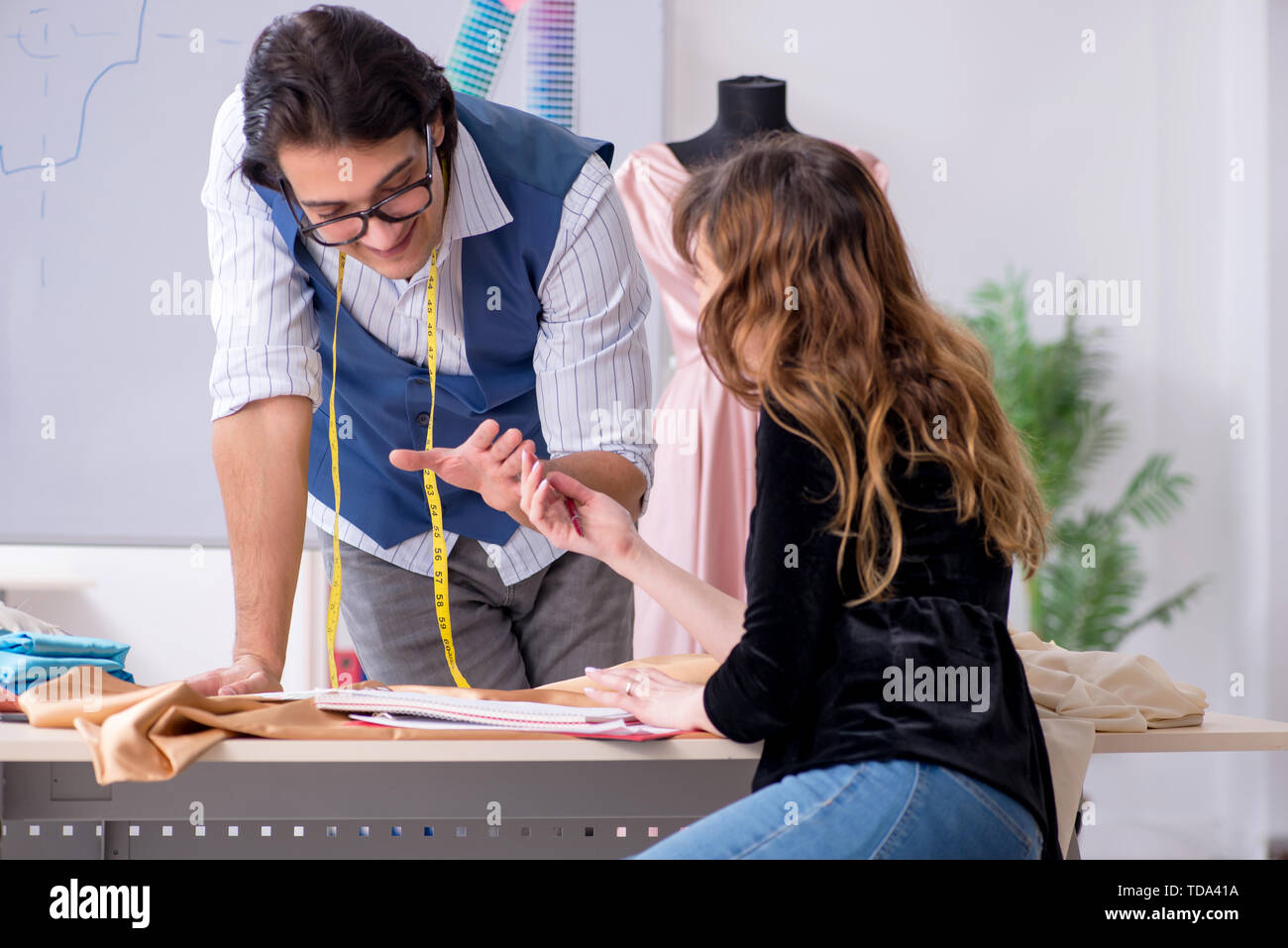 Young male tailor teaching female student Stock Photo - Alamy