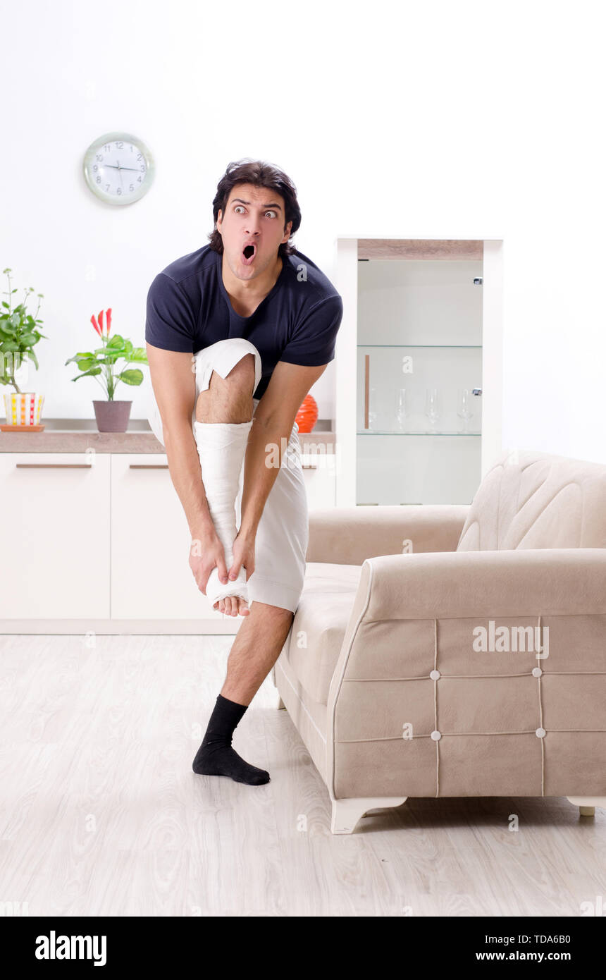 Leg injured young man suffering at home Stock Photo - Alamy