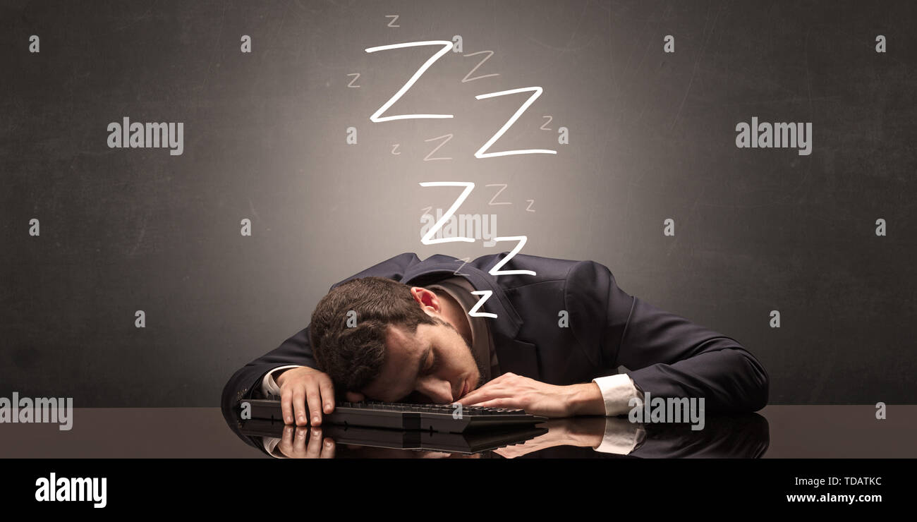 Young businessman fell asleep at the table on his keyboard concept ...