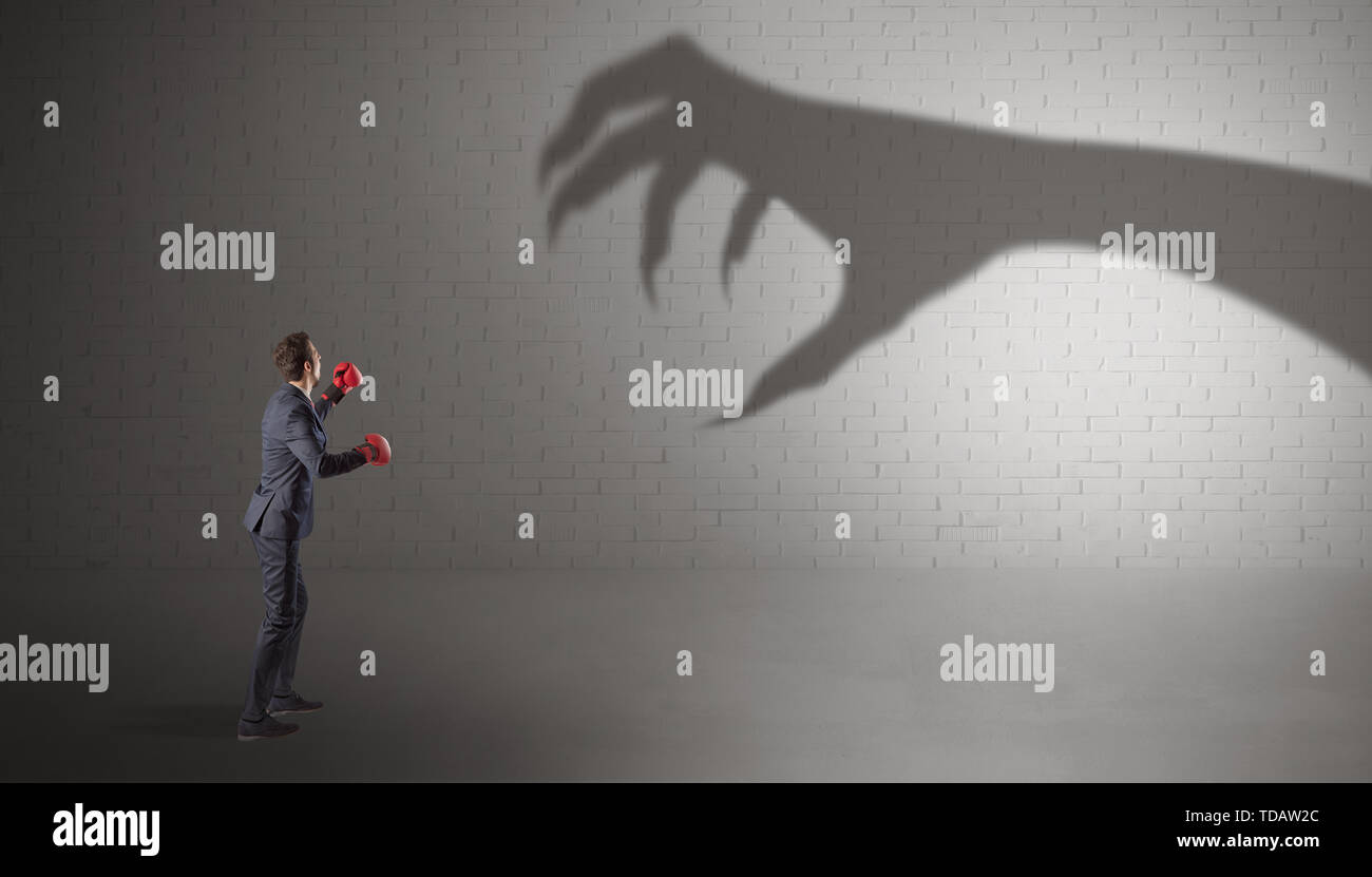 Tiny businessman fighting with scary hand shadow Stock Photo - Alamy