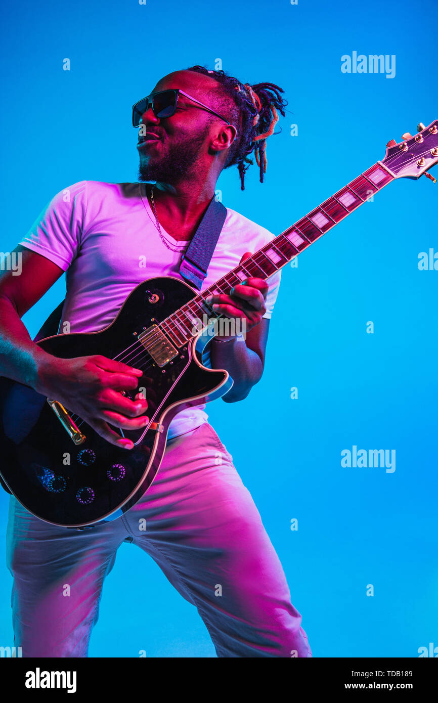 Young african-american musician playing the guitar like a rockstar on ...