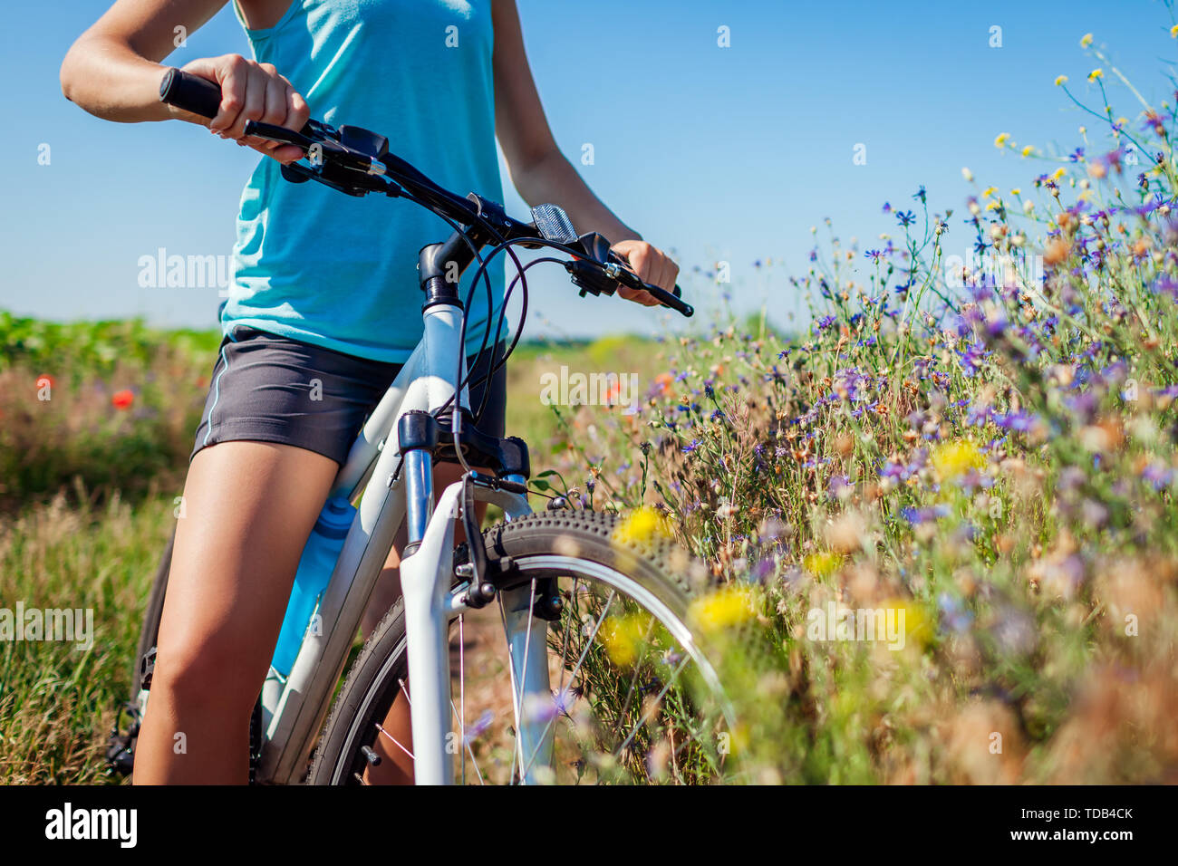 Young woman cyclist riding a mountain bicycle in summer field. Close up ...