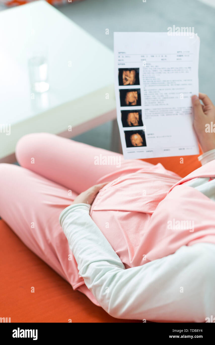 Photo of pregnant woman lying and looking at report Stock Photo - Alamy